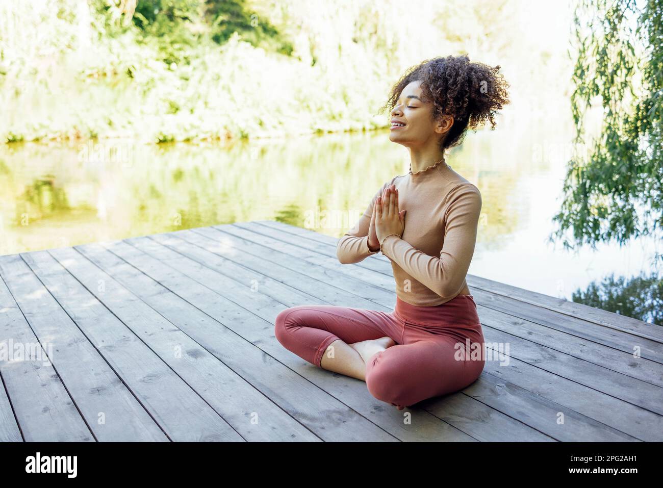 African american young girl is doing yoga asana in park. Smiling female ...