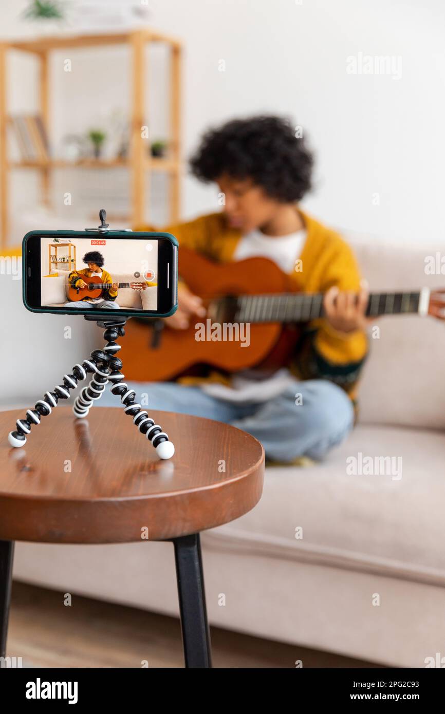 Blogger guitarist. Happy african american girl blogger playing guitar ...