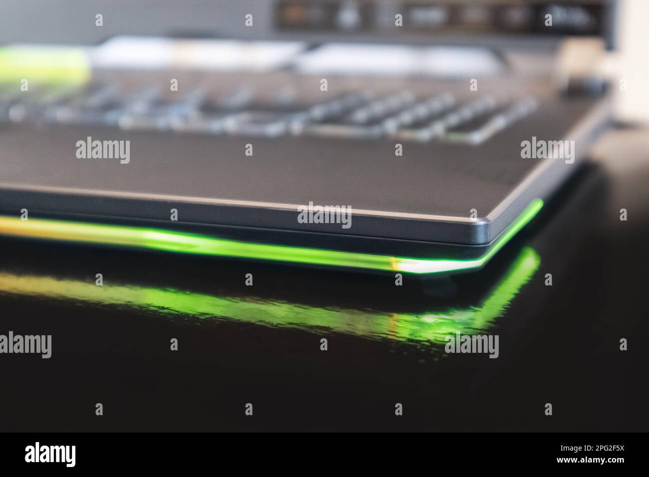 Laptop close-up with colorful green illumination. Gaming grey notebook ...