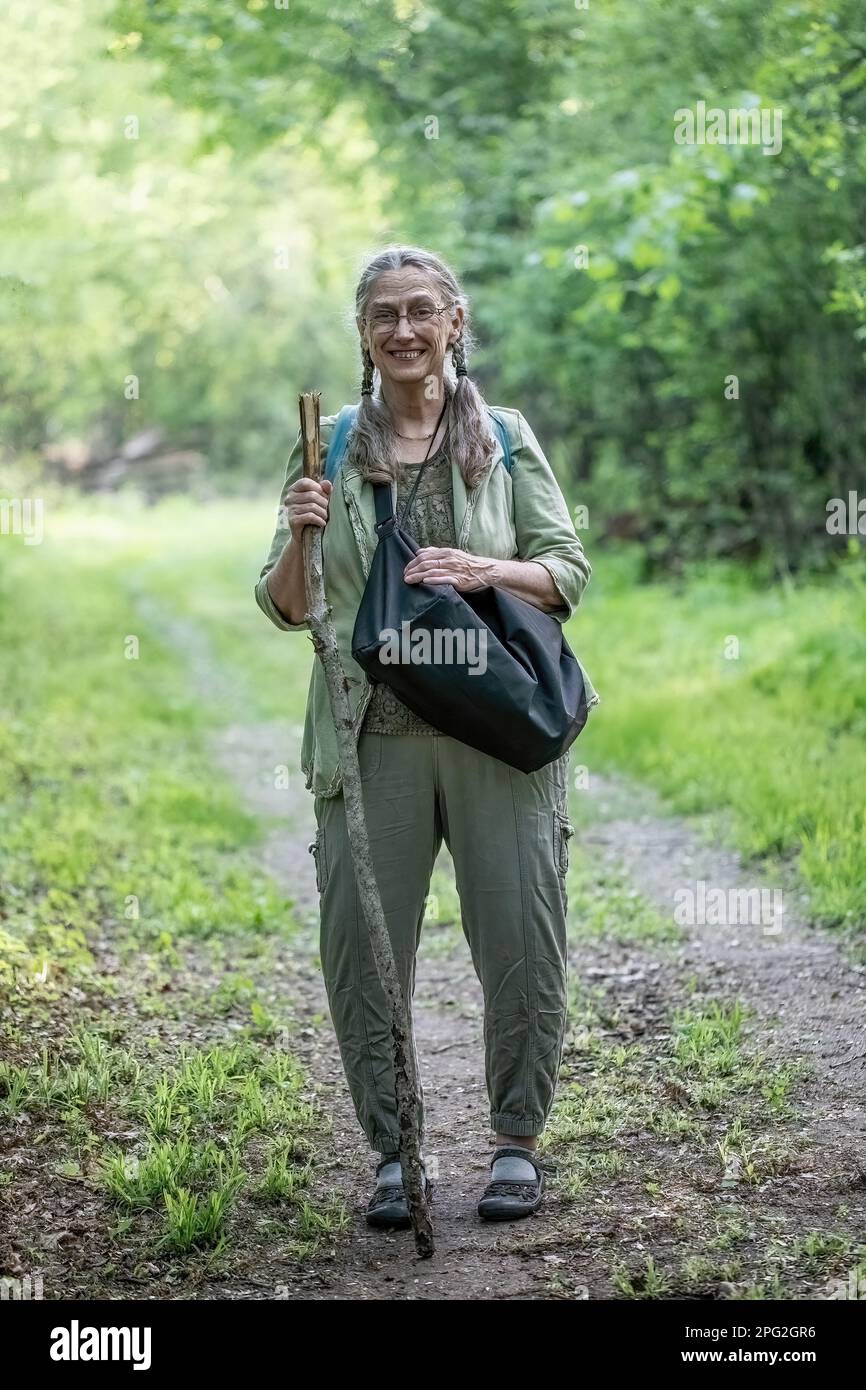 Mature woman with a walking stick hiking the springtime woods near ...
