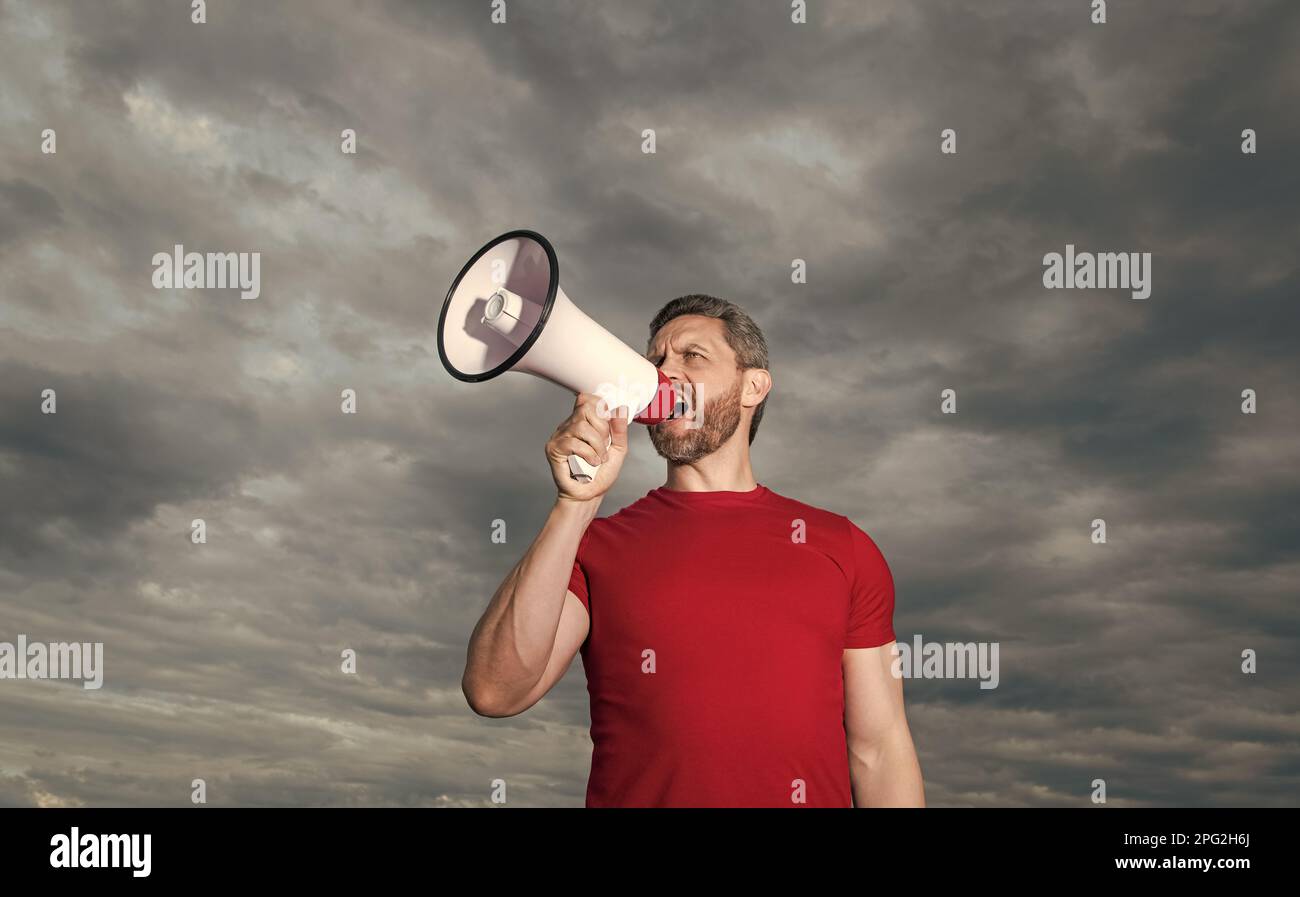 man in red shirt shout in loudspeaker on sky background. attention ...