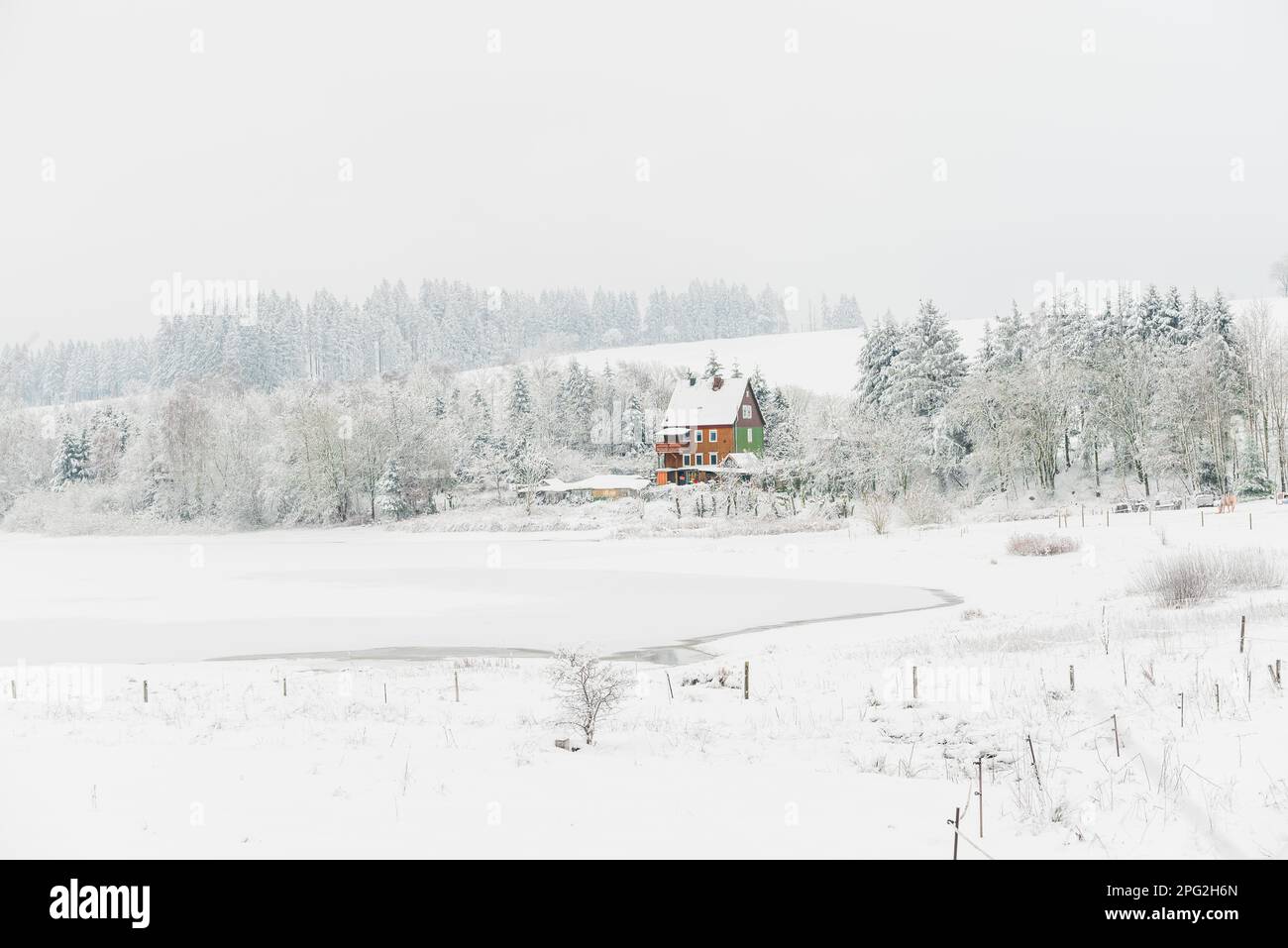 A tranquil rural winter scene with a farmhouse nestled among frost ...
