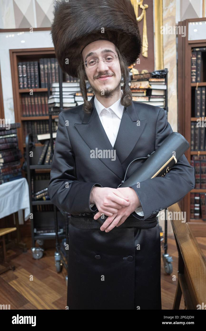 Posed portrait of an orthodox Jewish man wearing a streimel and holding ...