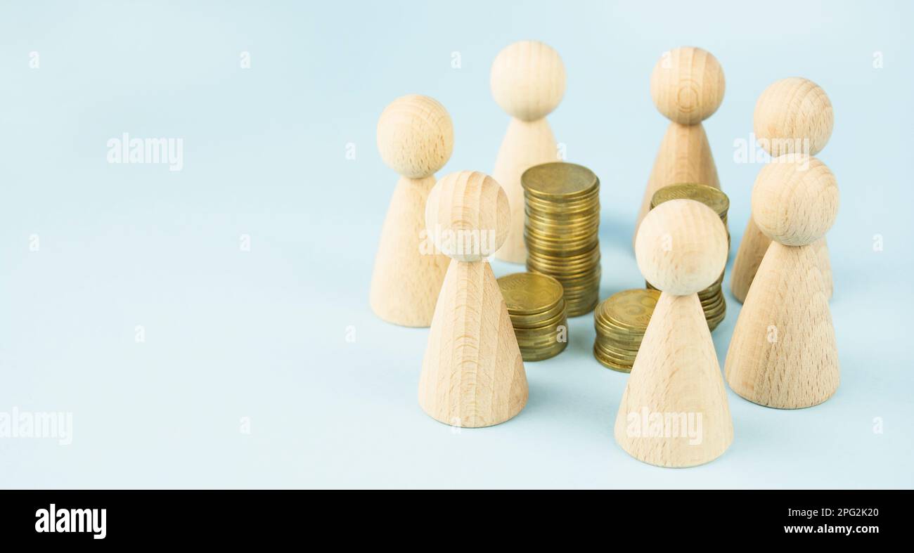 Business concept. Wooden figures of people stand around coins on a blue ...