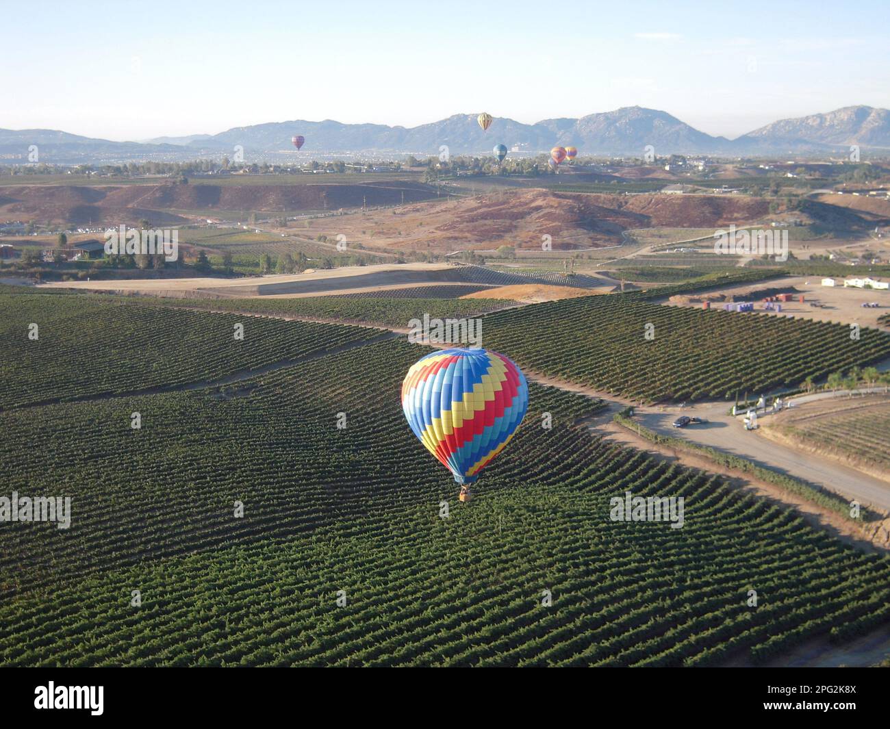 An aerial view of a hot air balloon hovering above a picturesque winery ...