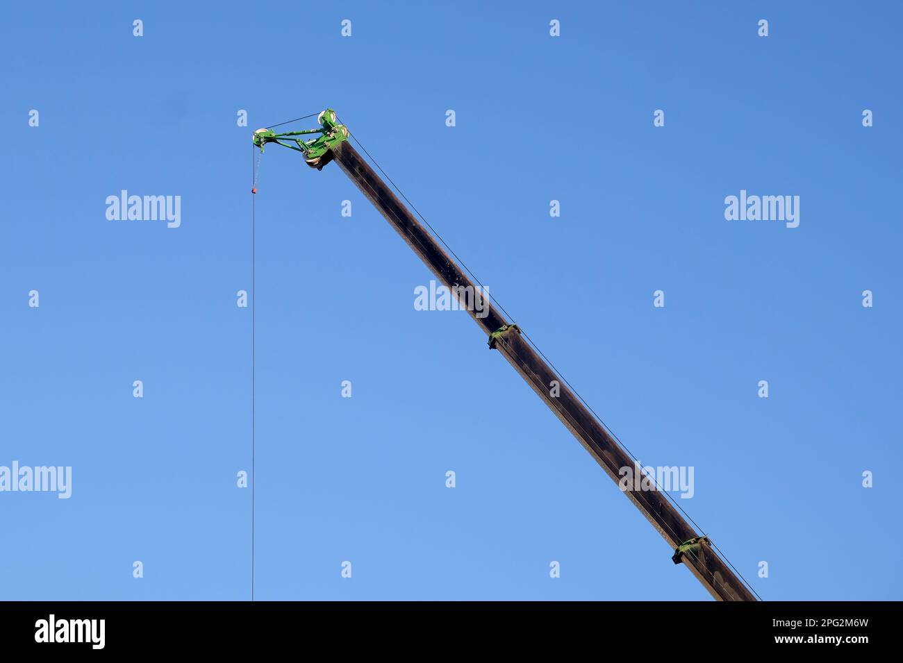 Long boom crane manipulator high in the blue cloudless sky Stock Photo ...
