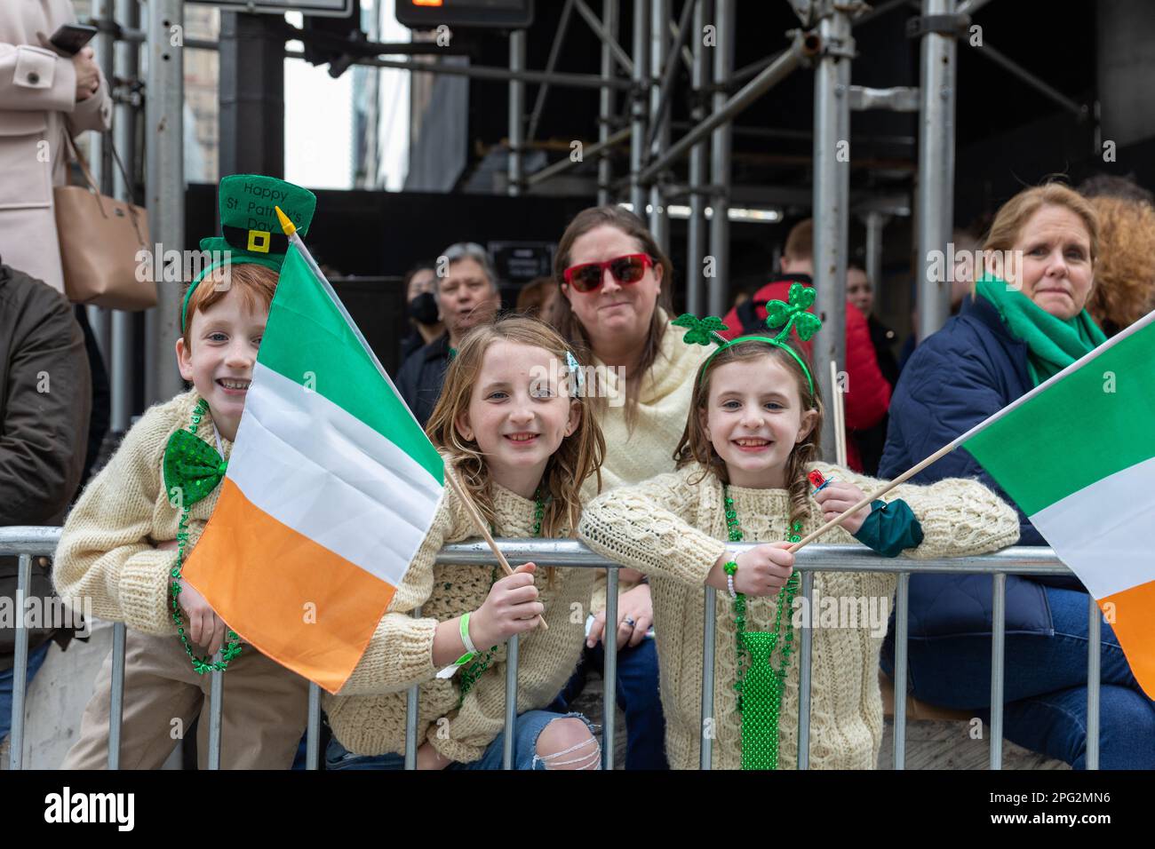 Three joyful young girls wearing shamrock-patterned glasses and waving ...
