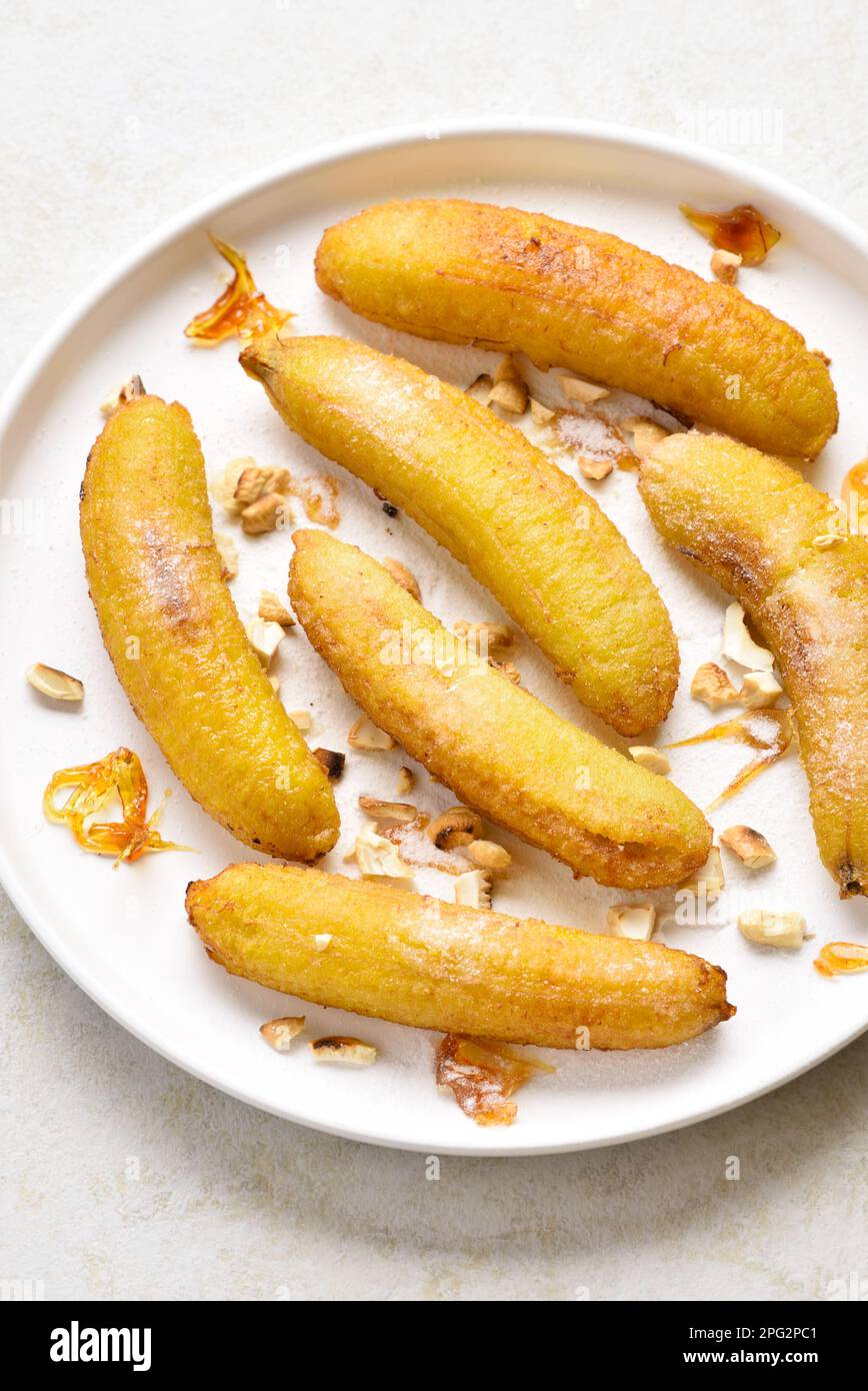 Deep fried bananas on plate over light stone background. Tasty dessert ...