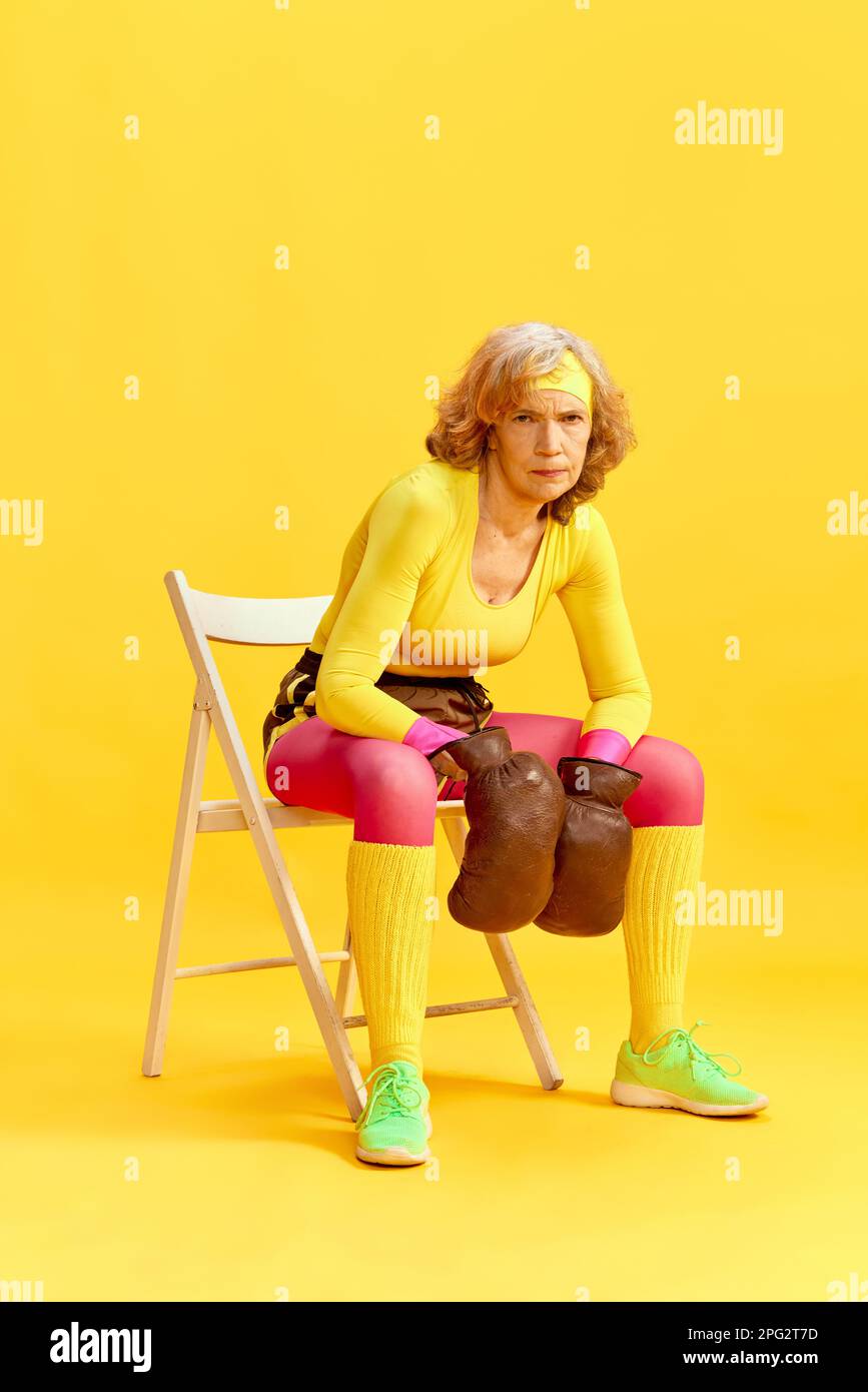 Middle-aged sportive woman in colorful uniform sitting on chair in ...