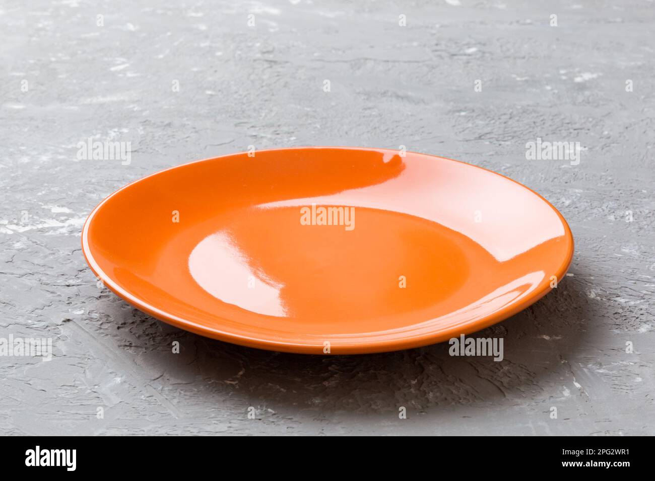 Perspective view of empty orange plate on cement background. Empty ...