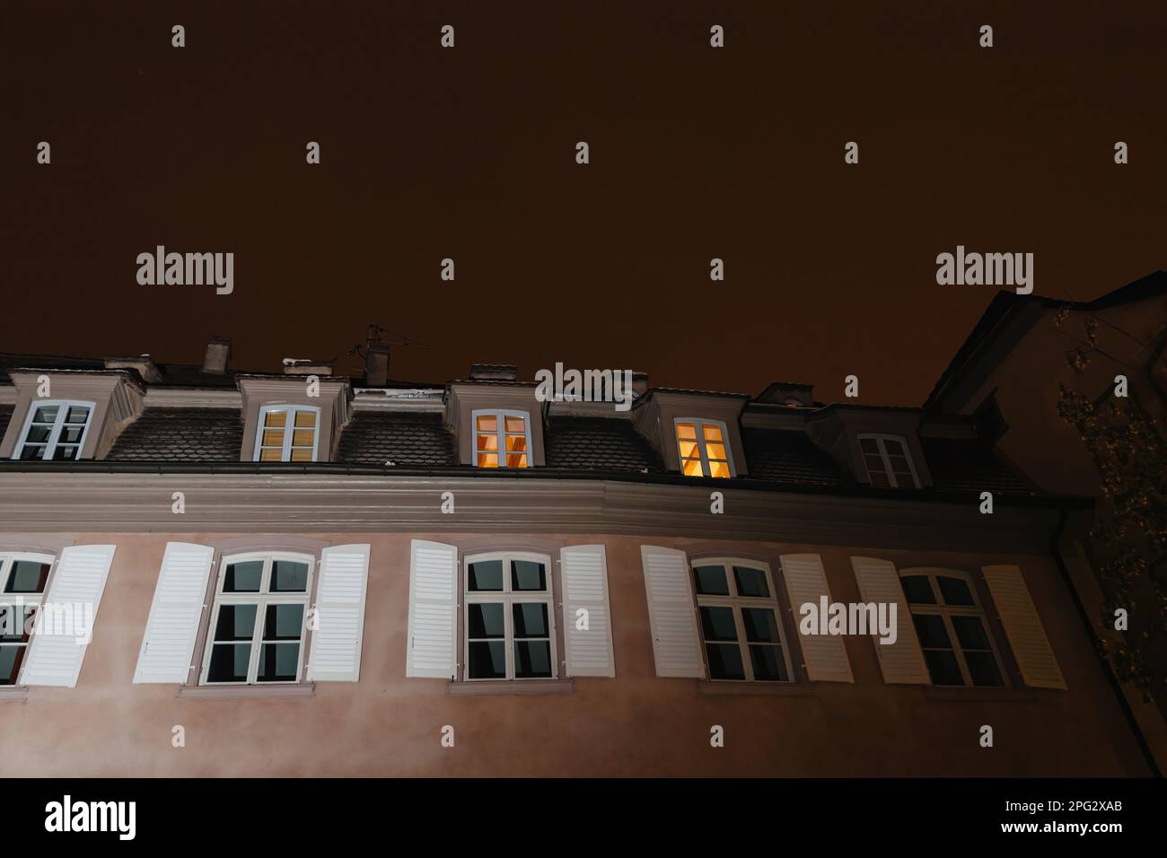 A night view of a house, illuminated by the soft glow from its windows ...