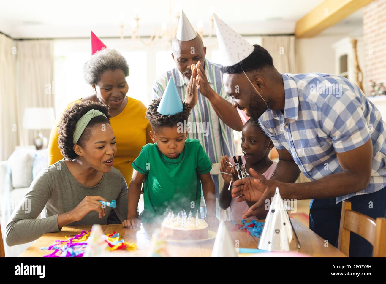 Happy african american family celebrating birthday, blowing candles ...