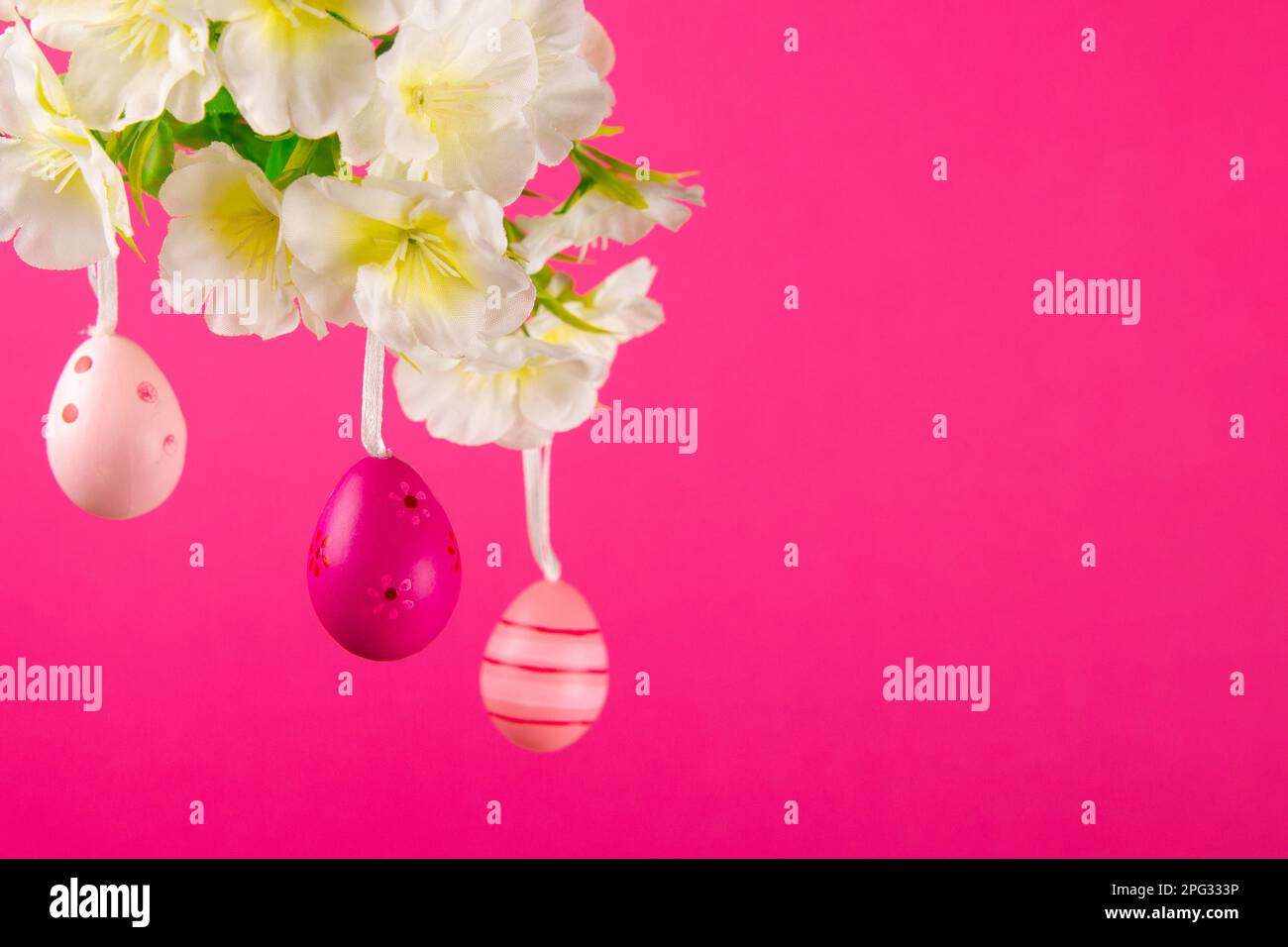 Three pastel pink Easter eggs dangle from a beautifully adorned branch ...