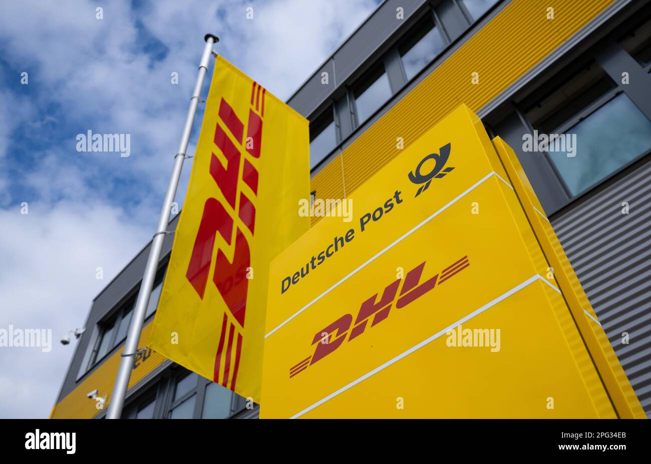 Aschheim, Germany. 20th Mar, 2023. A sign and a flag with the DHL logo ...