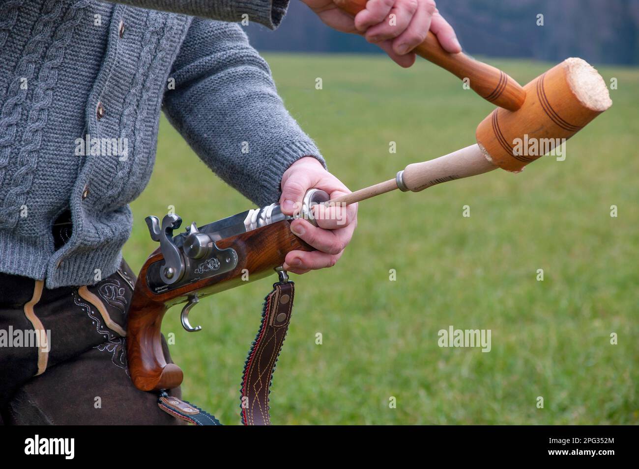 A shooter in tradtional dress loading its gun with gunpowder. Bavaria ...