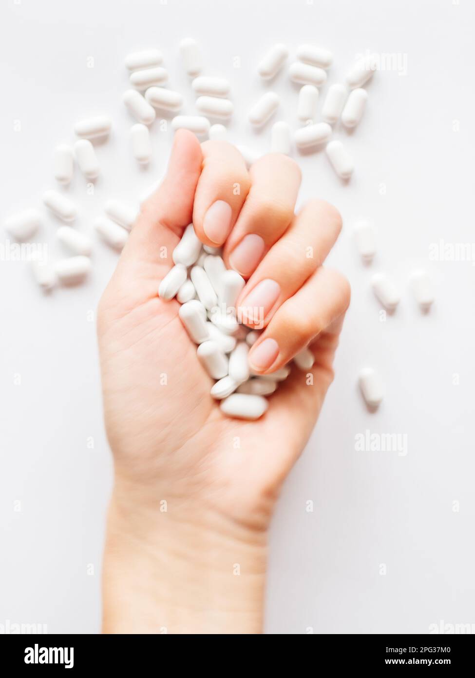 Palm hand full of white scattering pills. Woman gripes hand with ...