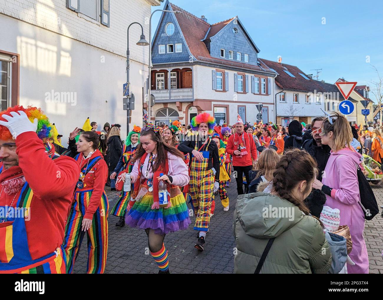 A group of people at a parade event wearing brightly-colored clown hats ...