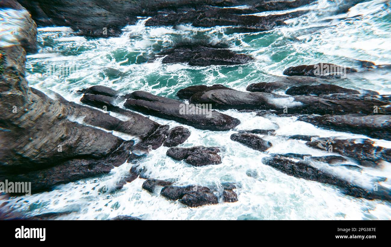 Ocean waters rushing against coastal sea rocks Stock Photo - Alamy
