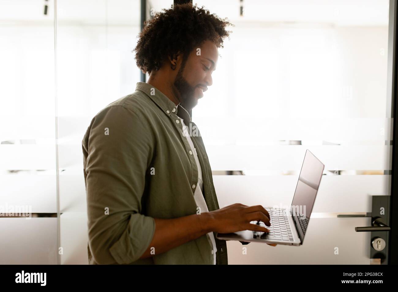 Concentrated man typing and working on a laptop remotely, standing in ...