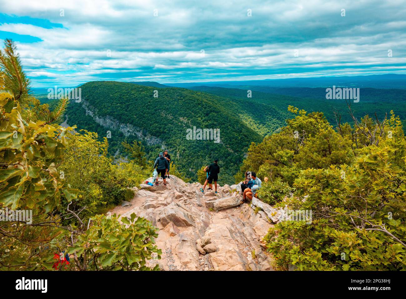 A group of hikers enjoying the view from a high elevation on a cliff ...