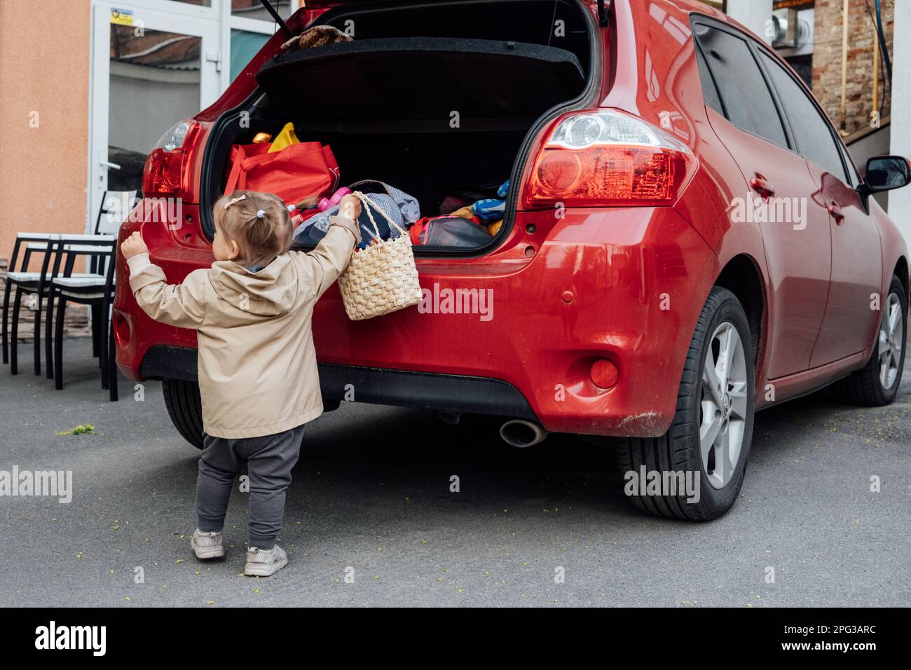 Family road trip where toddler little girl is helping to load up the ...