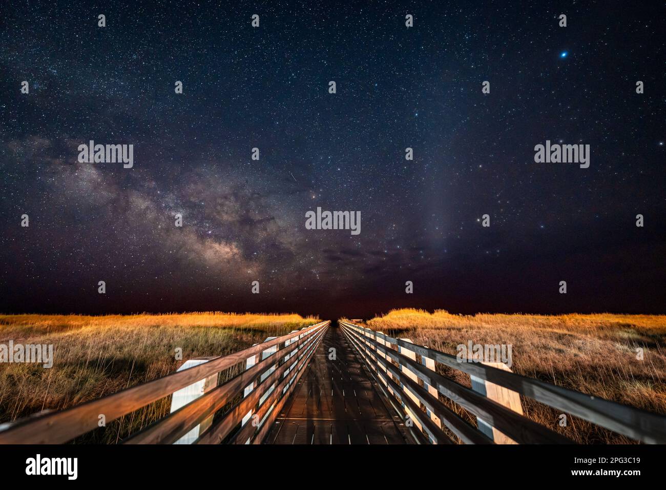 A wooden bridge illuminated by moonlight and starry night across a ...