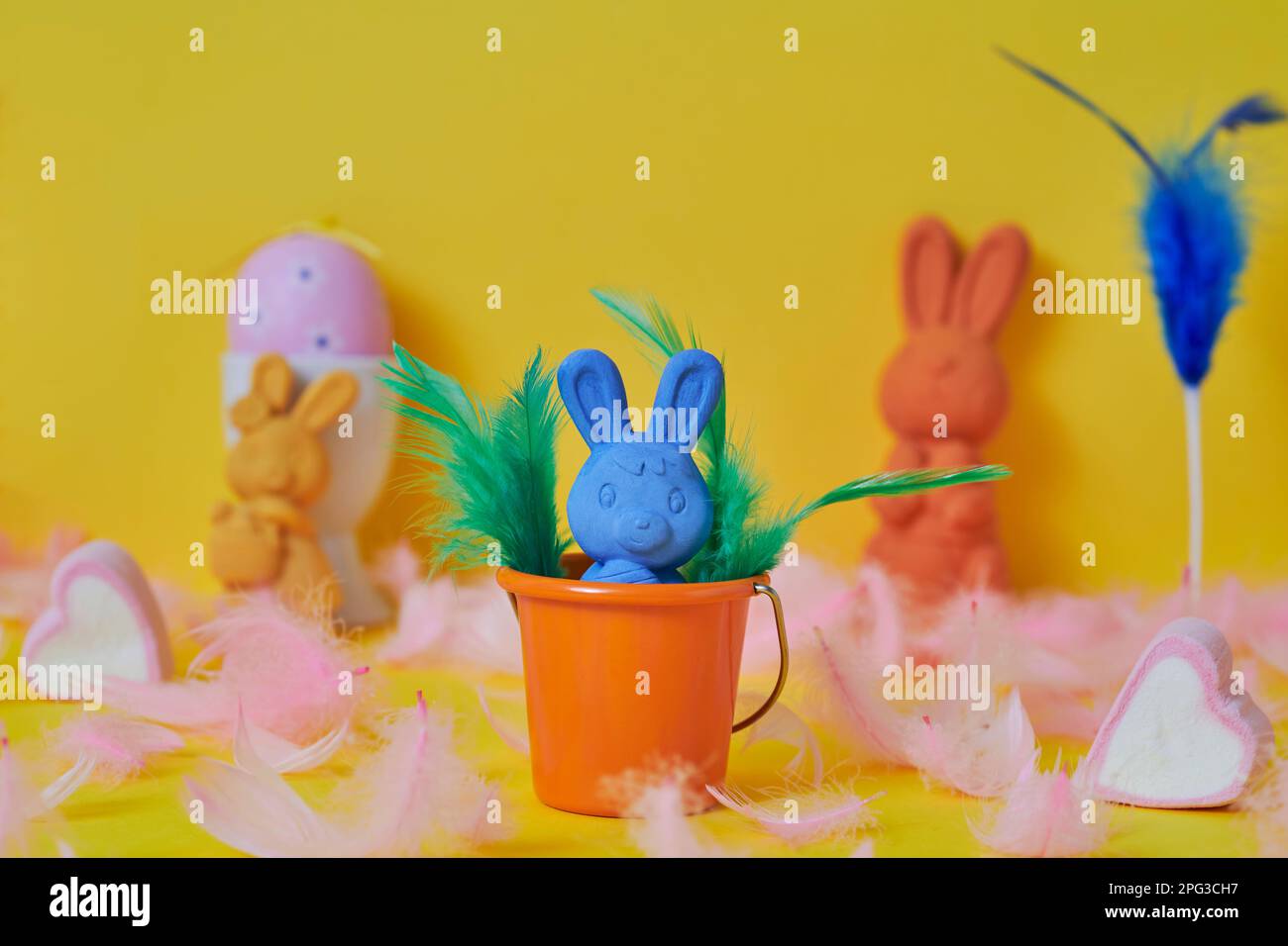 a blue easter bunny in an orange bucket surrounded by pink feathers and ...