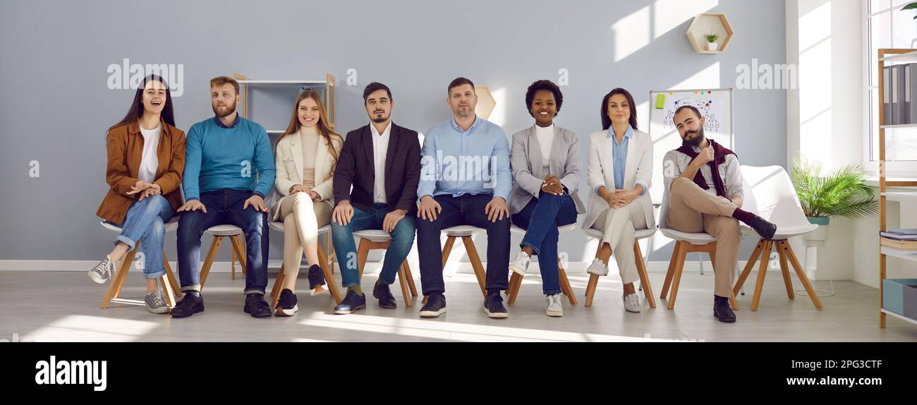 Portrait of group of people sitting in row on chairs and who are ...