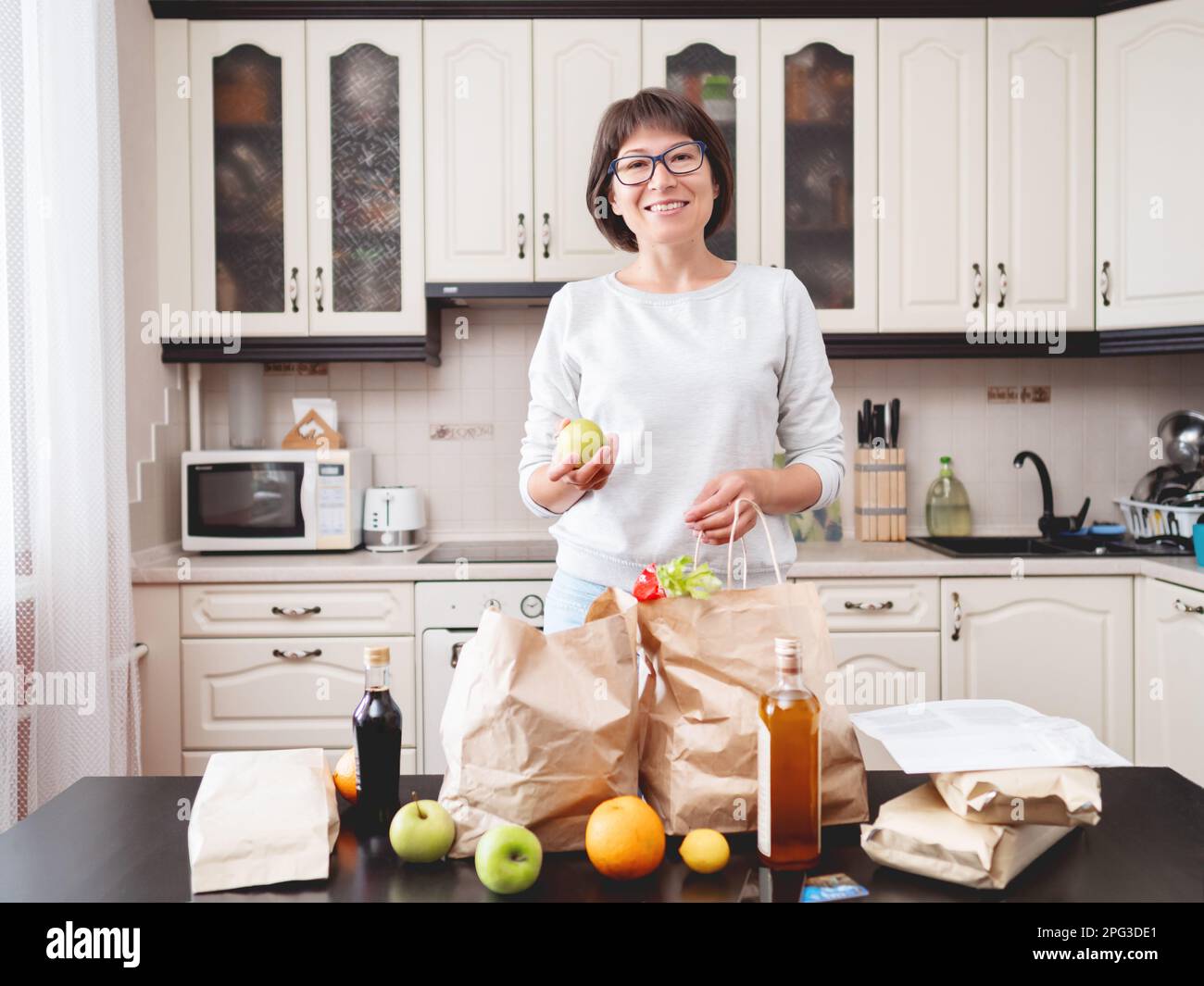Woman sorts out purchases in the kitchen. Grocery delivery in paper ...
