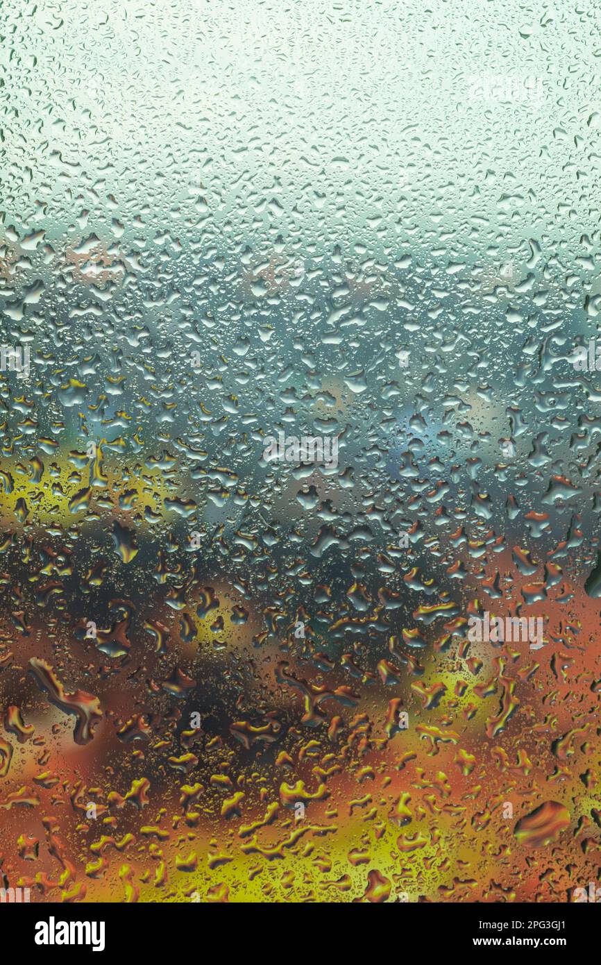 Raindrops on glass during rain, large drops. Landscape with raindrops falling on the window of ...