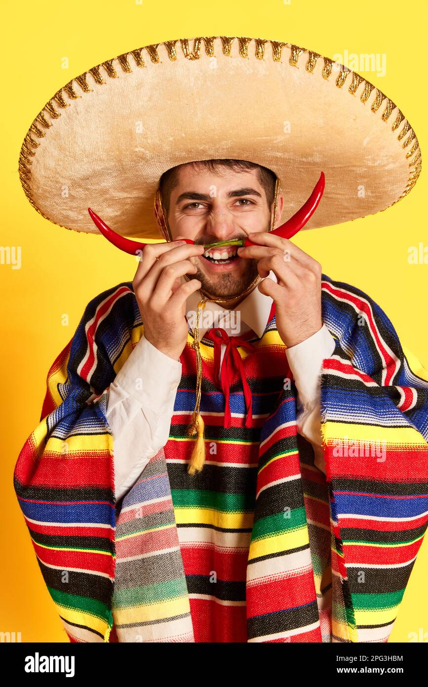 Portrait of young man in colorful festive clothes, poncho and sombrero ...
