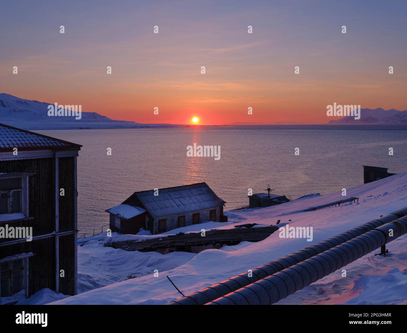 Sunset over the mine. Russian coal mining town Barentsburg at fjord ...