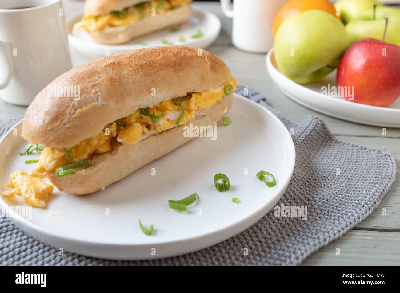 Breakfast baguette bun with scrambled egg and chives on kitchen table ...