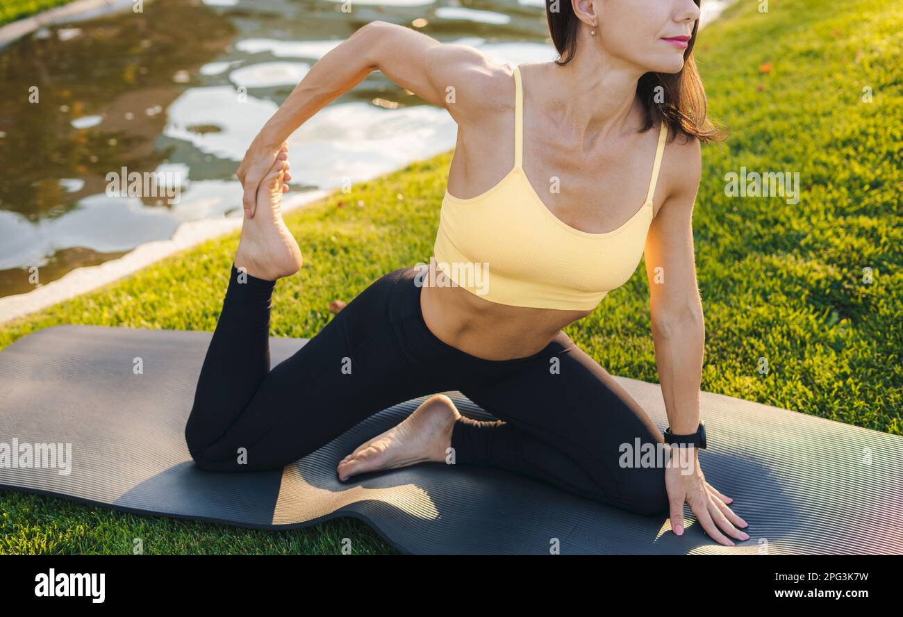 Sporty cheerful lady in yellow top and black leggings stretching leg ...
