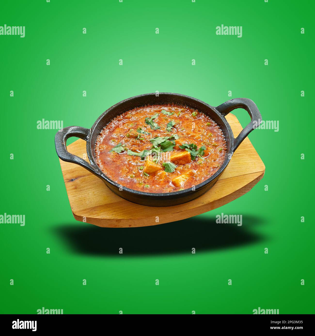 Floating matar paneer baked in little pan on green gradient background ...