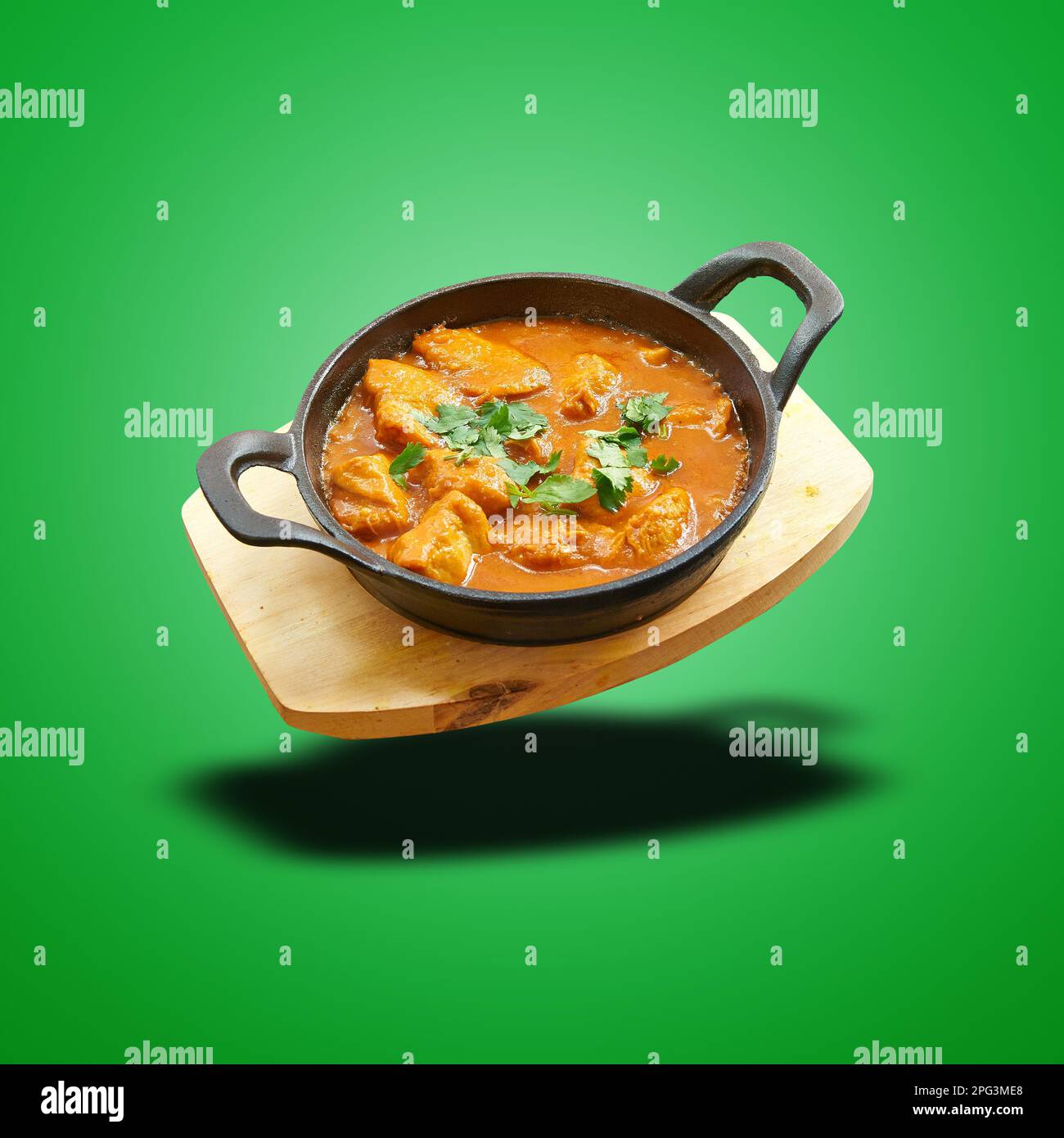 Floating Chicken curry baked in little pan on green gradient background ...