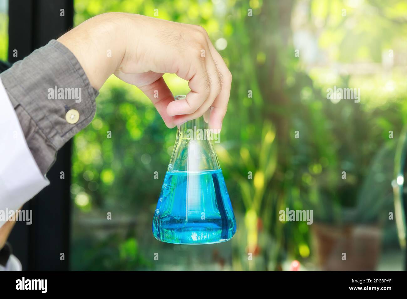Beaker with blue experiment liquid in scientist hand on laboratory ...