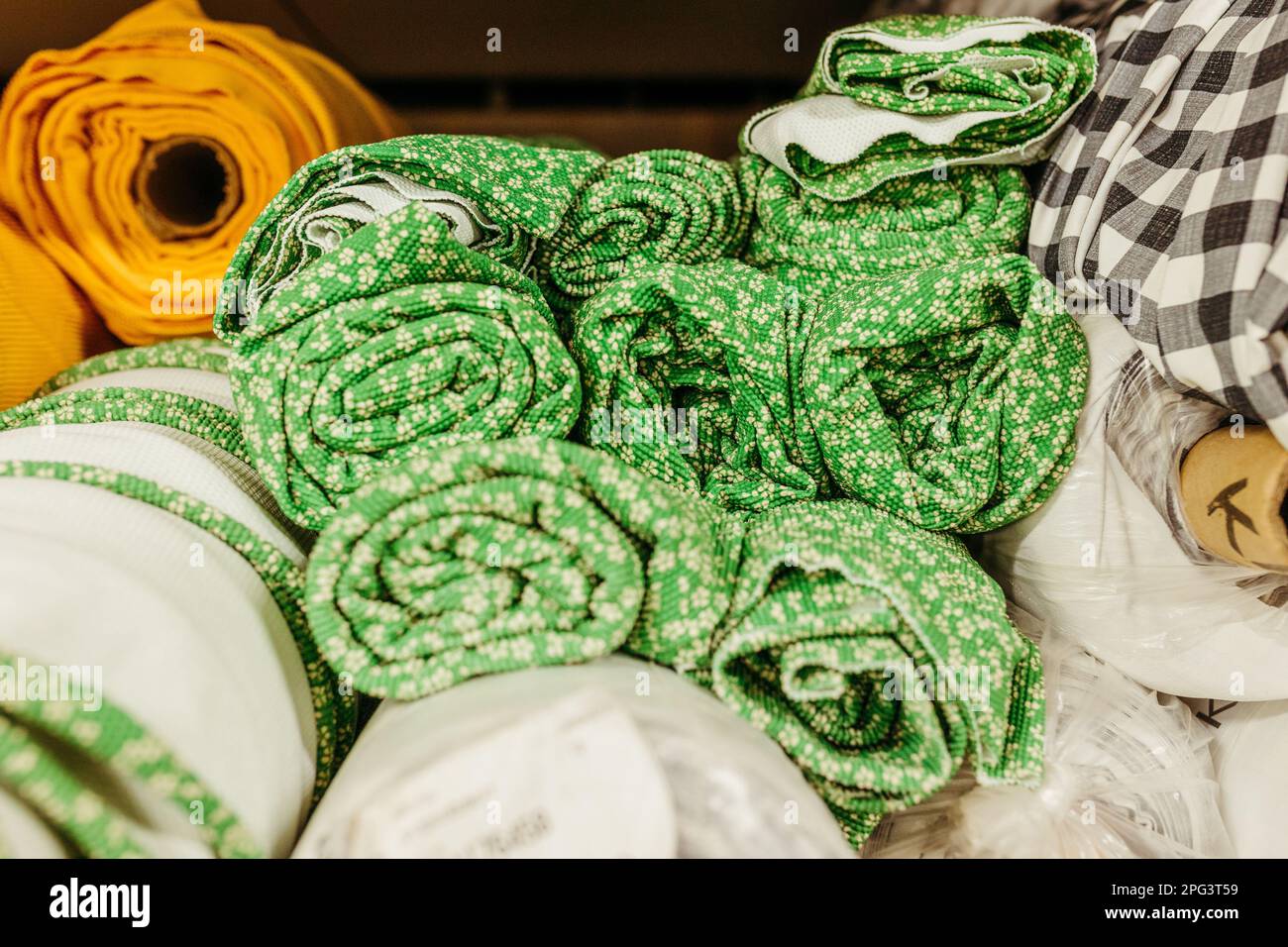 A collection of vibrant green knitted fabric rolls arranged in a neat ...