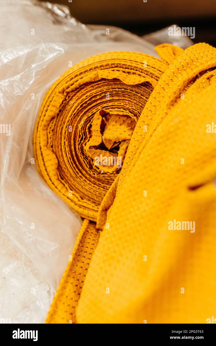 A collection of vibrant mustard colored knitted fabric rolls arranged ...