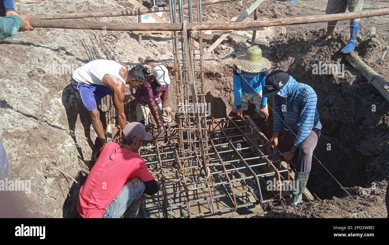 Workers on a construction site work together to manually lift the ...