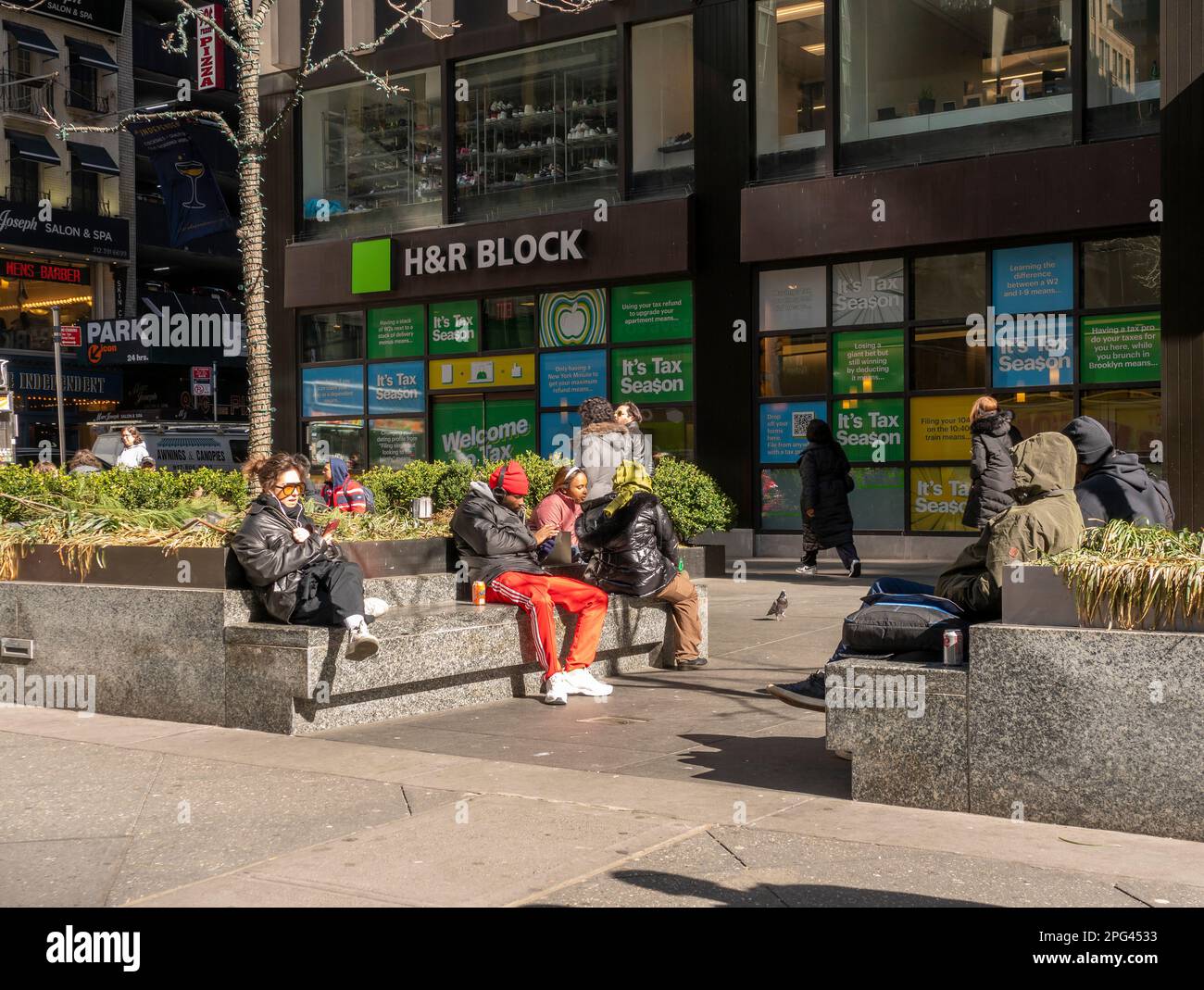 People enjoy the sun in a plaza in front of an H&R Block office in the ...