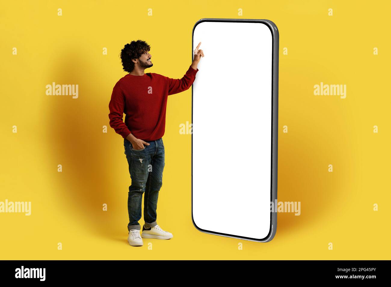 Happy indian man touching huge phone white screen on yellow Stock Photo ...