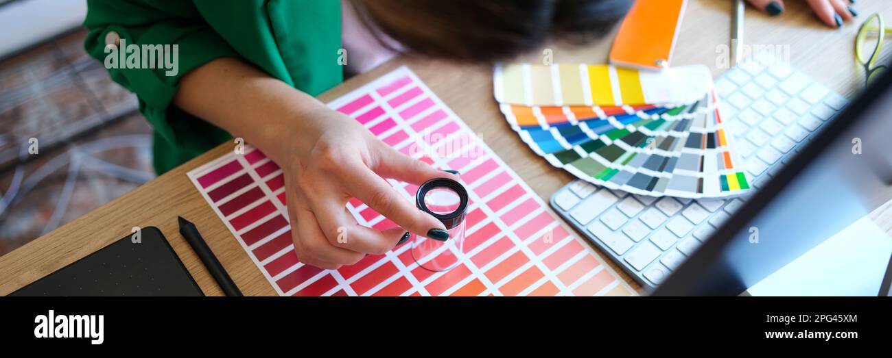 Woman chooses through magnifying glass color and shades on color ...