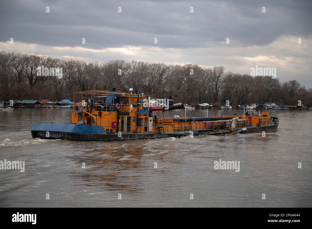 A river barge sailing down the river passing a row of floating houses ...