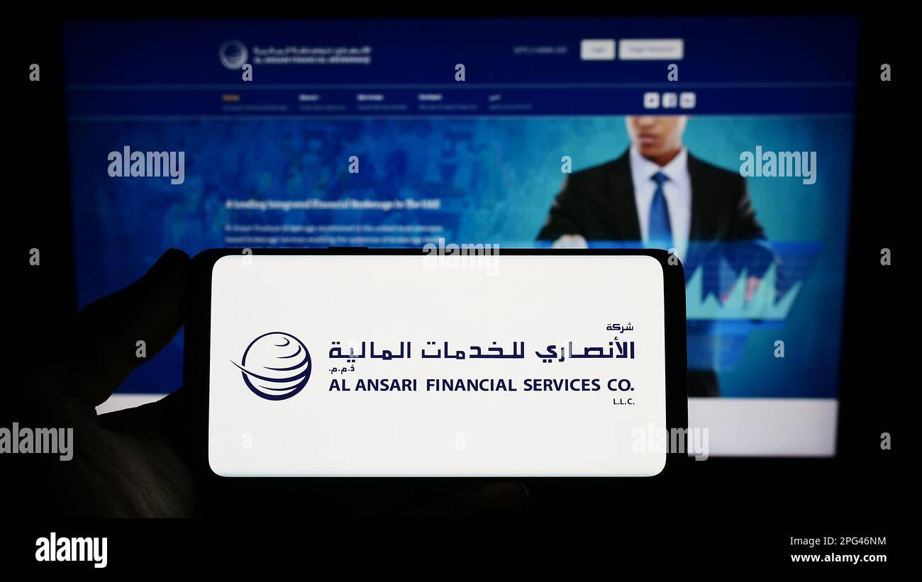 Person holding smartphone with logo of Arabian company Al Ansari ...