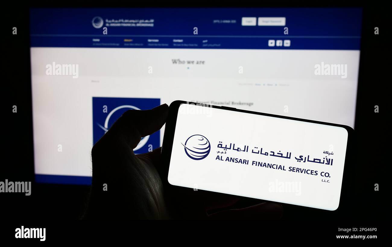 Person holding mobile phone with logo of Arabian company Al Ansari ...