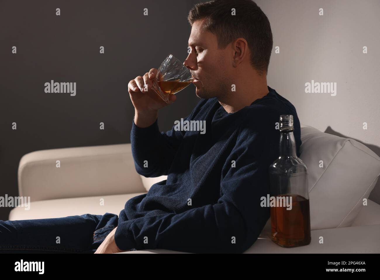 Addicted man drinking alcohol on sofa indoors Stock Photo - Alamy