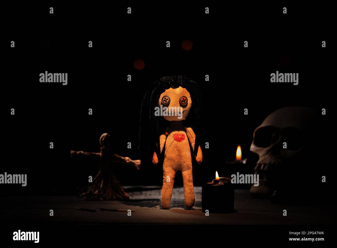 Female voodoo doll with pin in heart and ceremonial items on table in ...