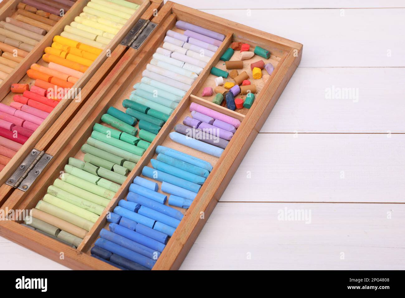 Set of soft pastels in box on white wooden table, space for text ...