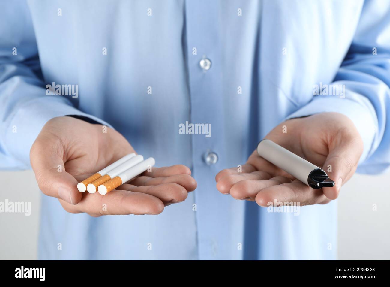 Man with cigarettes and vaping device on light background, closeup ...